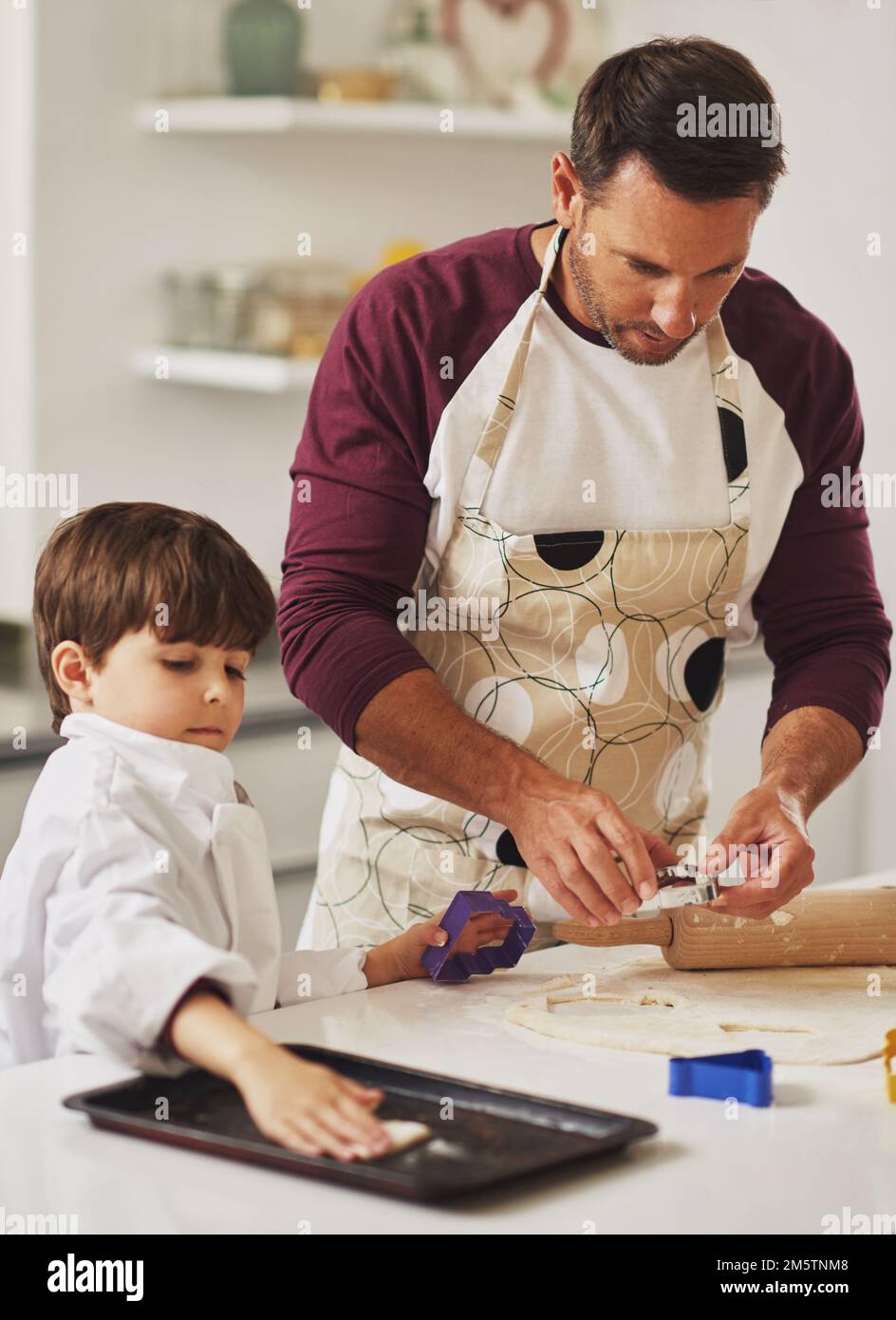 The boys are baking. a father and his young son baking cookies together ...