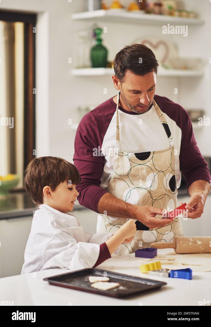 Baked by the boys. a father and his young son baking cookies together ...