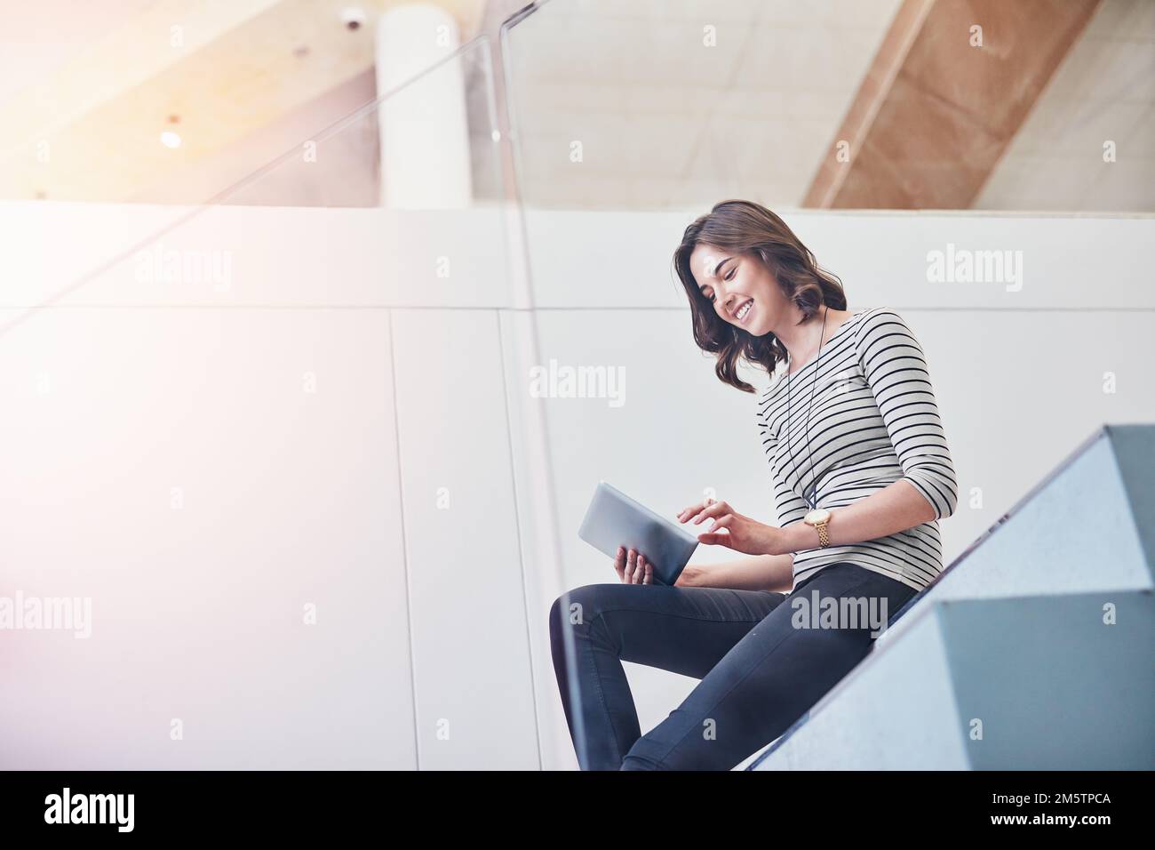 I work where I want. a young designer using her tablet while sitting on ...