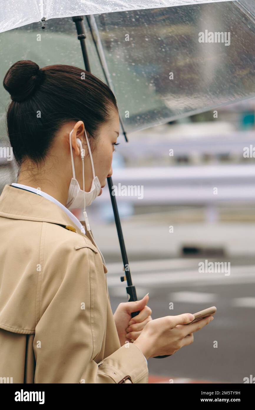 Women using phone in the rain Stock Photo - Alamy