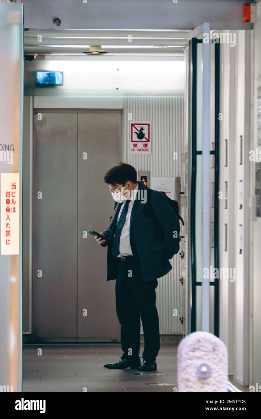 Middle aged corporate worker using phone while waiting for the elevator ...