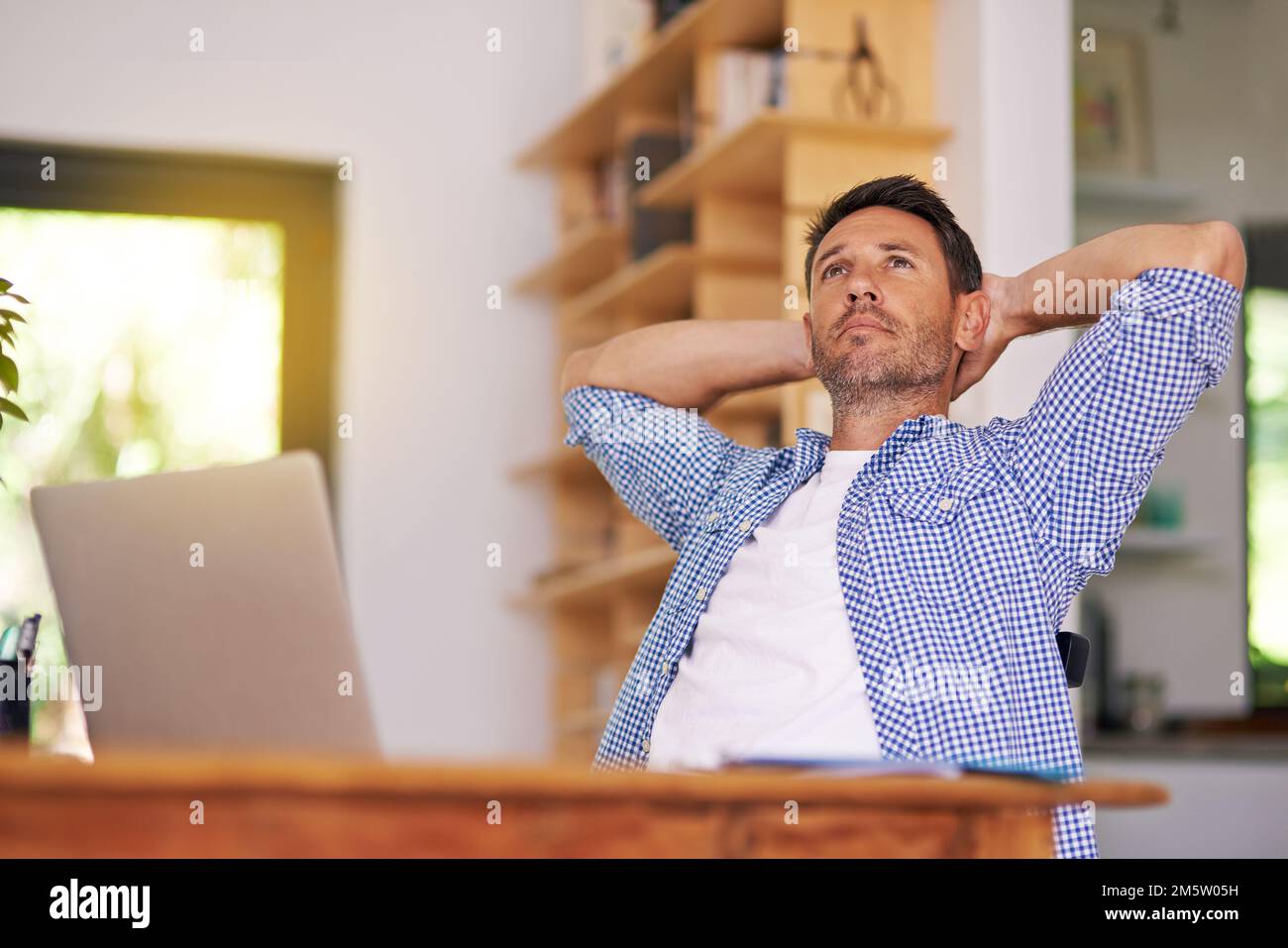Getting comfortable in his home office. a young man working from home ...