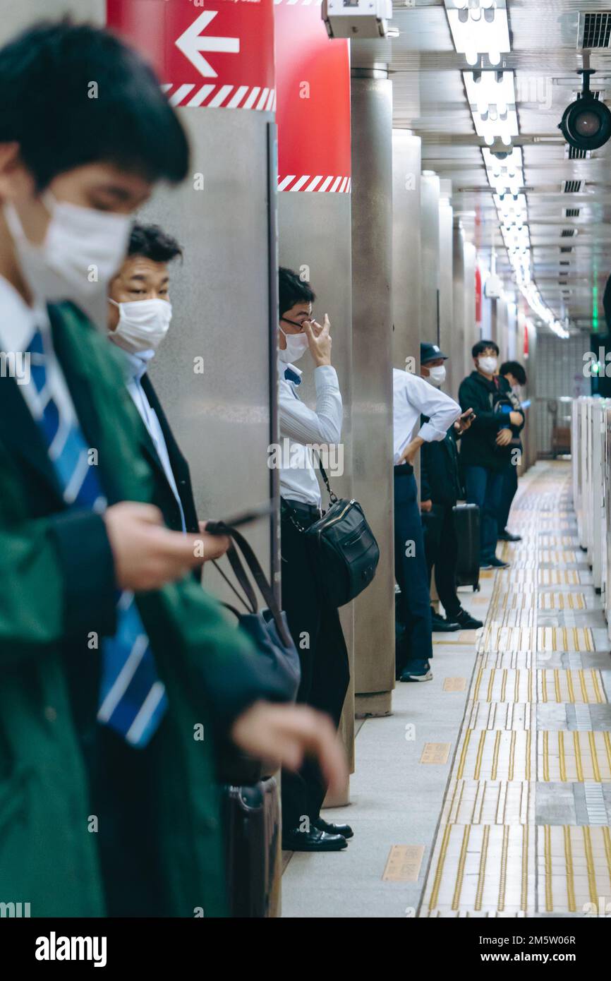 a row of commuters waiting in line for the train to arrive Stock Photo ...