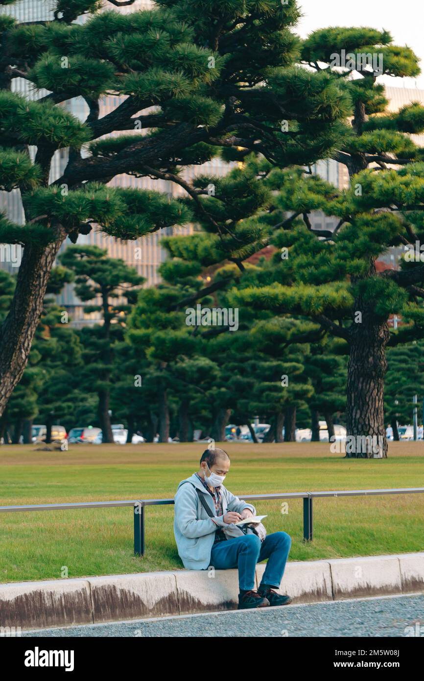 A man sitting and writing in a park Stock Photo - Alamy