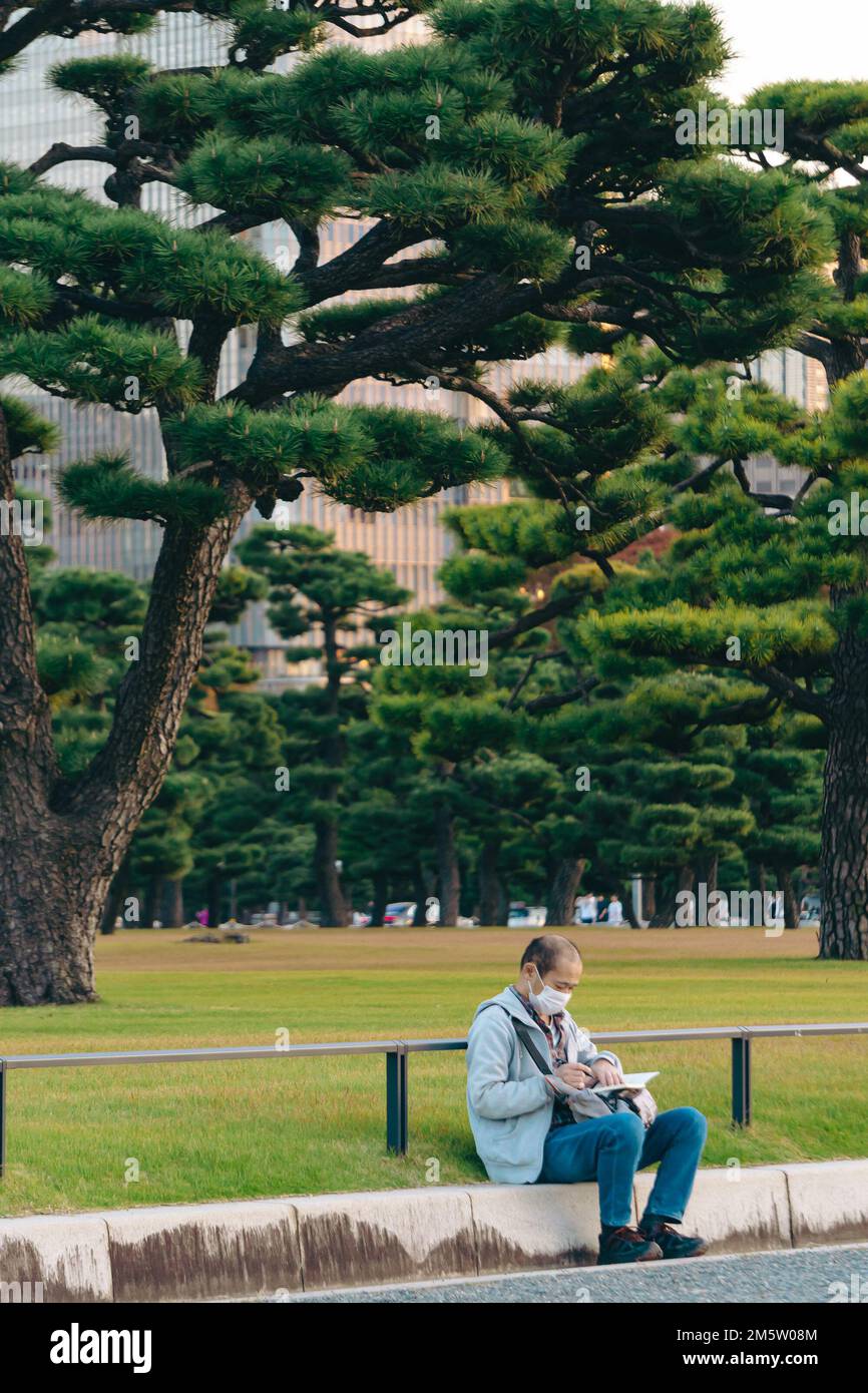 A man sitting and writing in a park Stock Photo - Alamy
