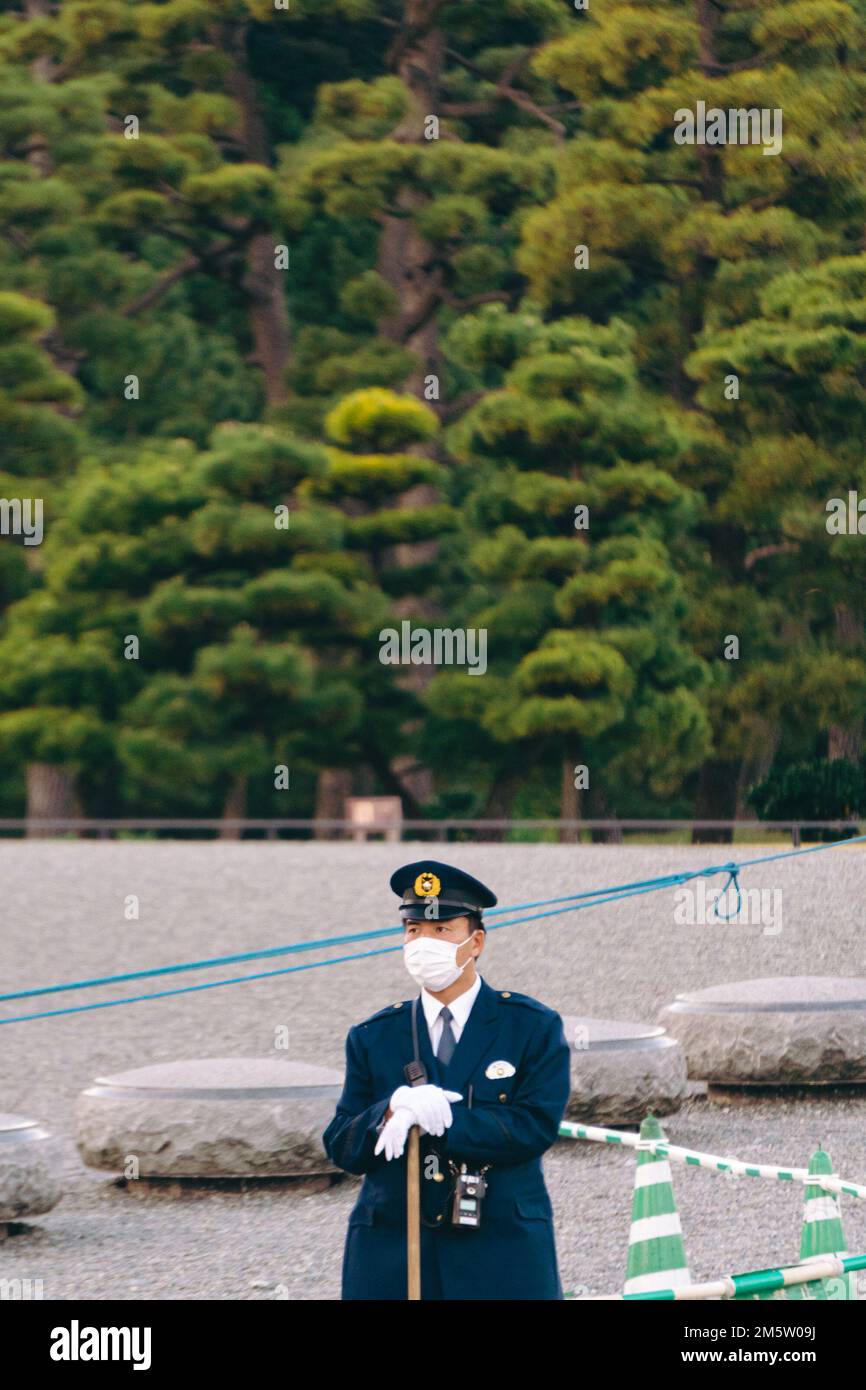 A security officer wearing a mask on duty at the entrance of Tokyo ...