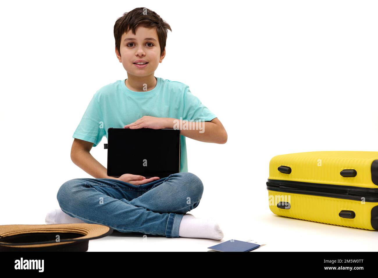 Traveler boy shows at camera a digital tablet with blank screen with ...