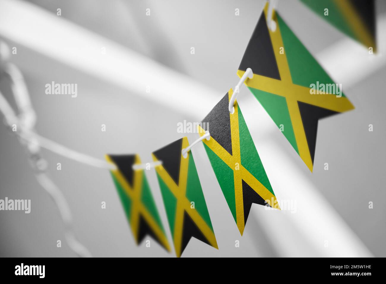 A garland of Jamaica national flags on an abstract blurred background ...