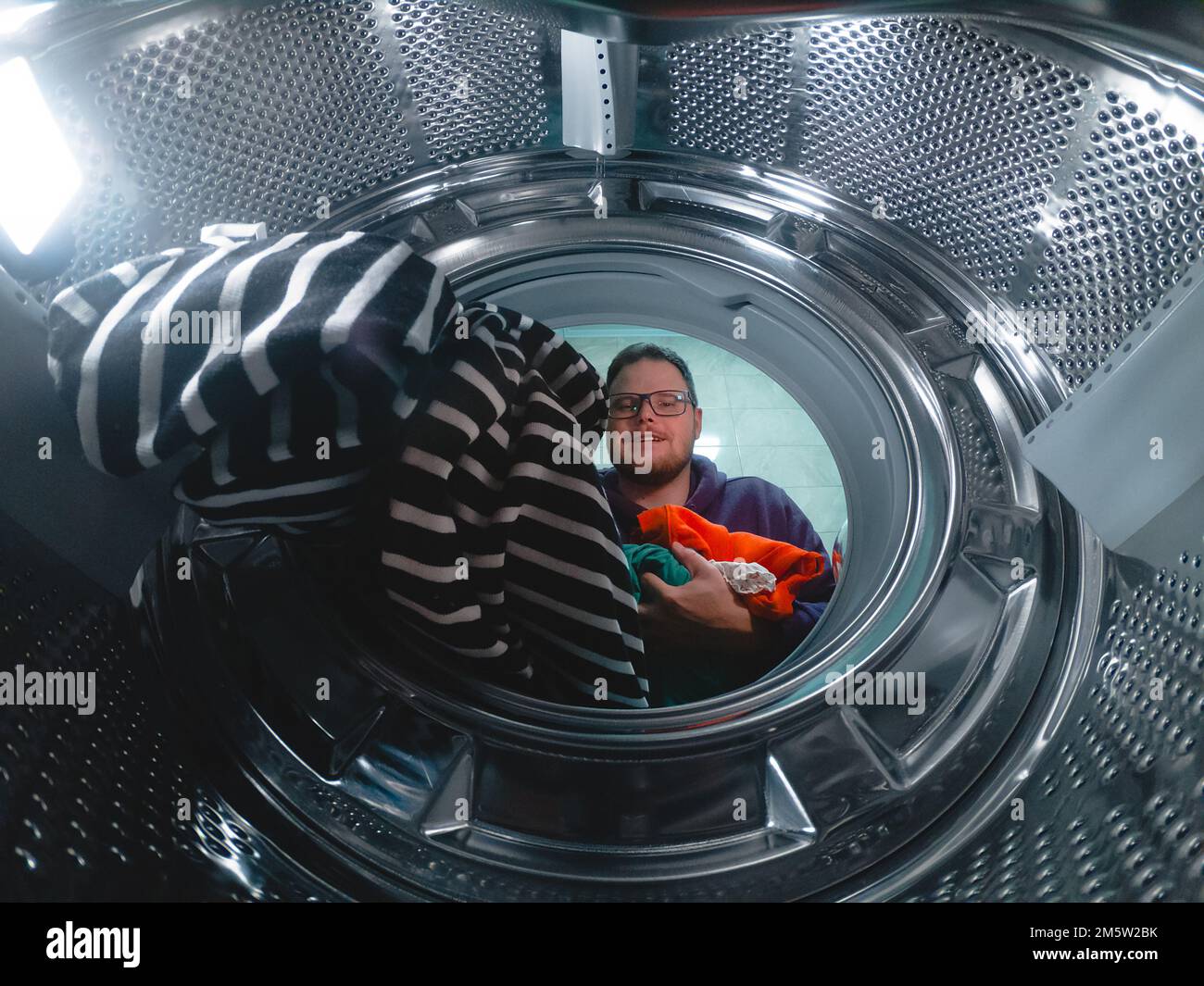 Washing machine is loaded with dirty clothes by a man Stock Photo - Alamy