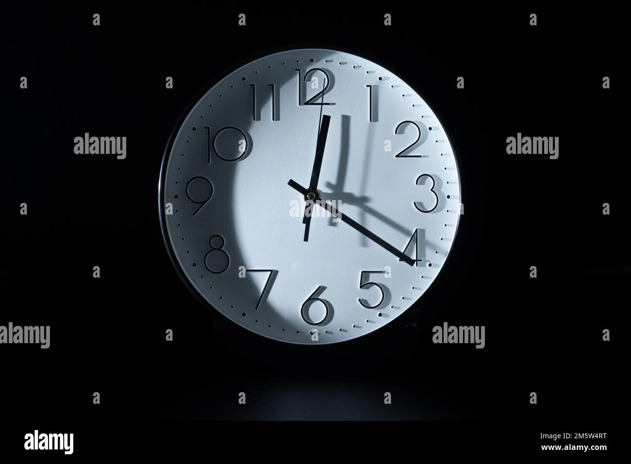 A closeup of a white clock showing twelve 20 on a dark background Stock ...