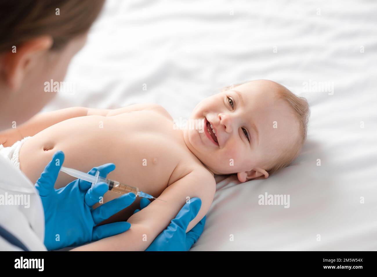 Doctor vaccinating baby in clinic. Little baby get an injection ...
