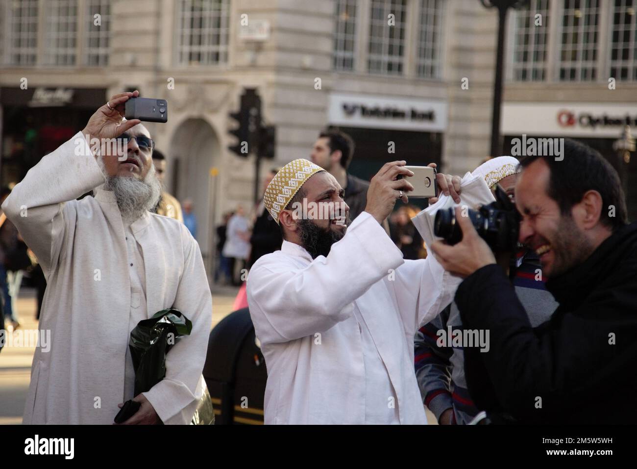 Two Arab men taking photos at Piccadilly Circus, London, UK Stock Photo ...
