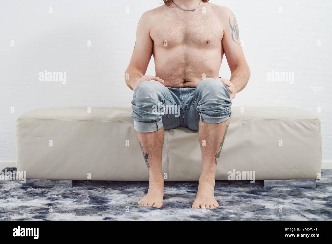 Man sitting barefoot on couch Stock Photo - Alamy