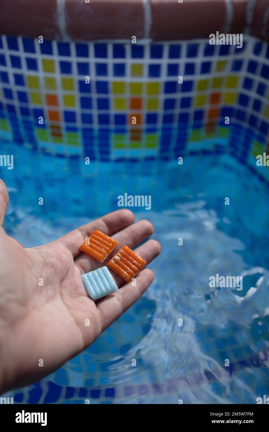 Hand holding small tile from walls of swimming pool. Design of the ...