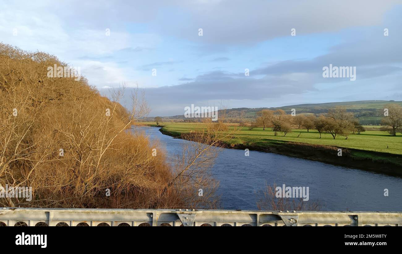 A scenic landscape of a river flowing through green fields during ...