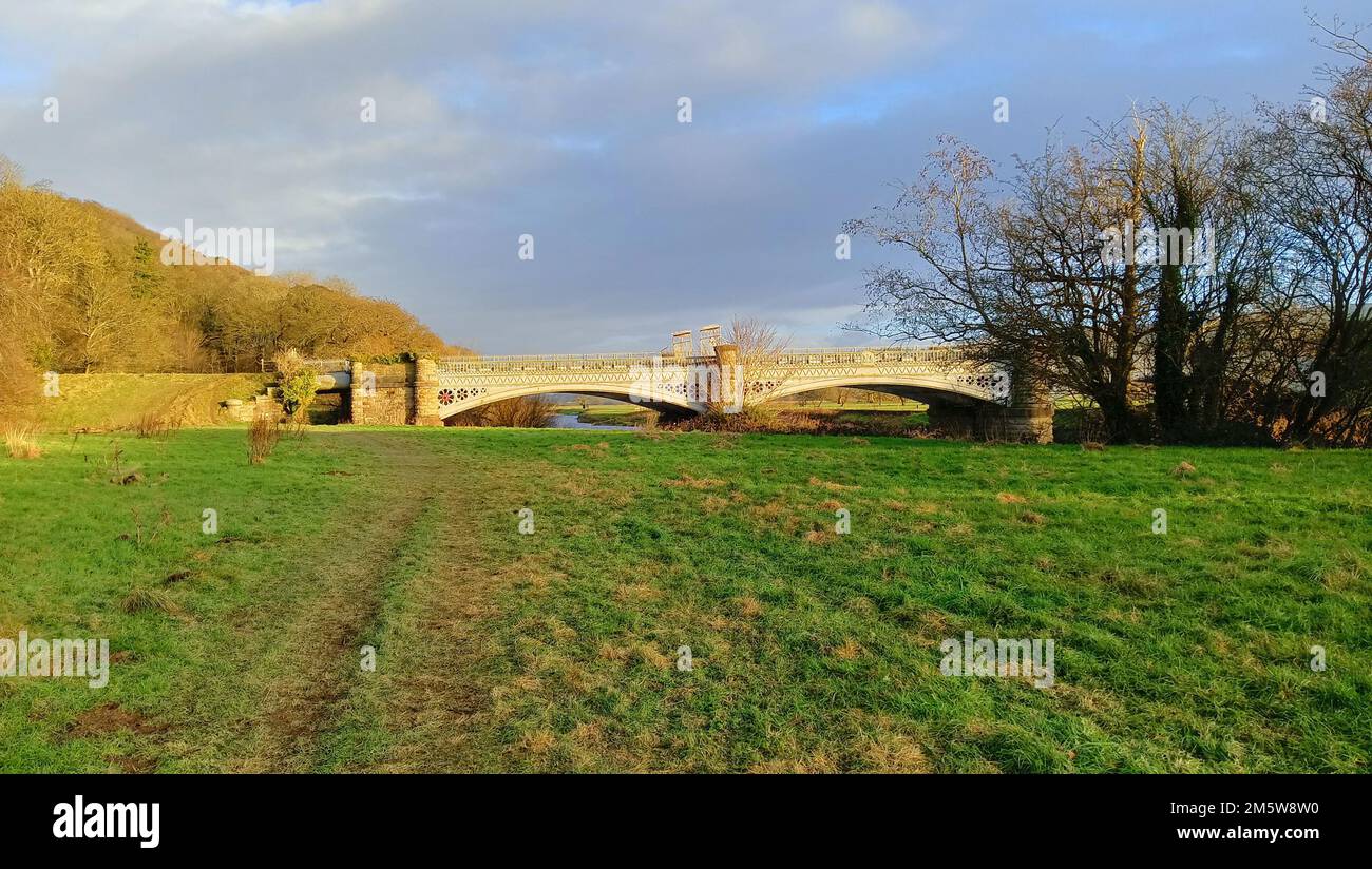 A scenic landscape of a grass field with a bridge in the background ...