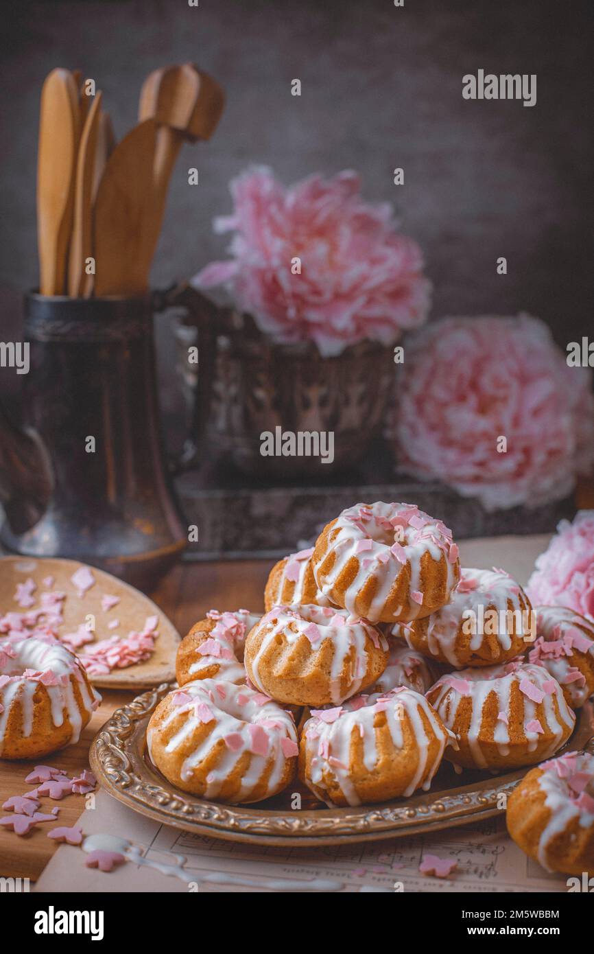 Muffins with pink icing in front of peonies (Paeonia Stock Photo - Alamy