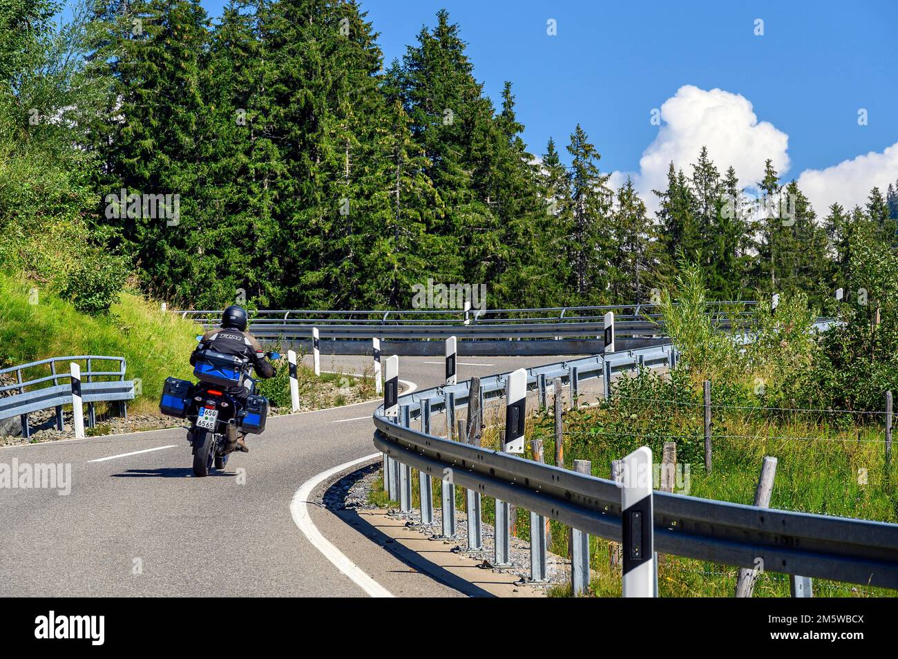 Motorcyclist in an S-curve on a road with crash barrier and underride ...