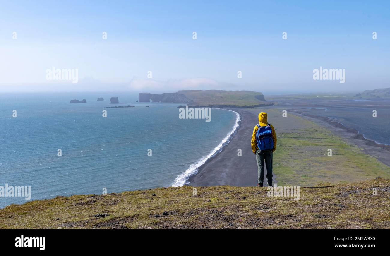 Tourist on rocky coast, view over Reynisfjara beach, black sand beach ...