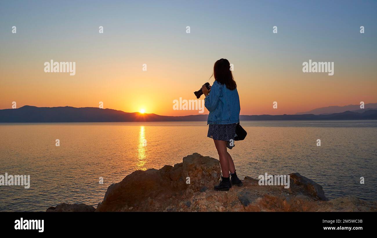 Sunrise, sun reflection on the sea, orange-blue cloudless sky, girl ...