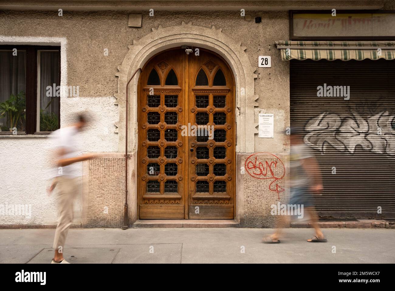 Two people passing an old arching wooden gate Stock Photo - Alamy