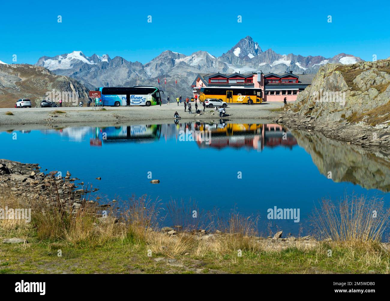 Coach with tourists and yellow bus of the Swiss PostBus AG on the ...