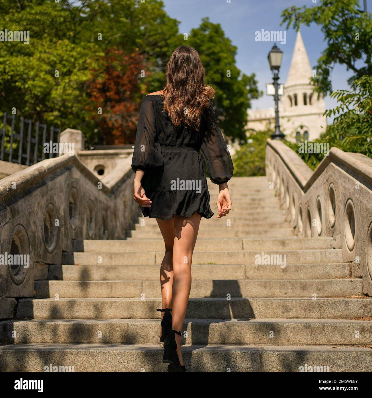 Model girl in black dress walking up stone heritage stairs Stock Photo ...