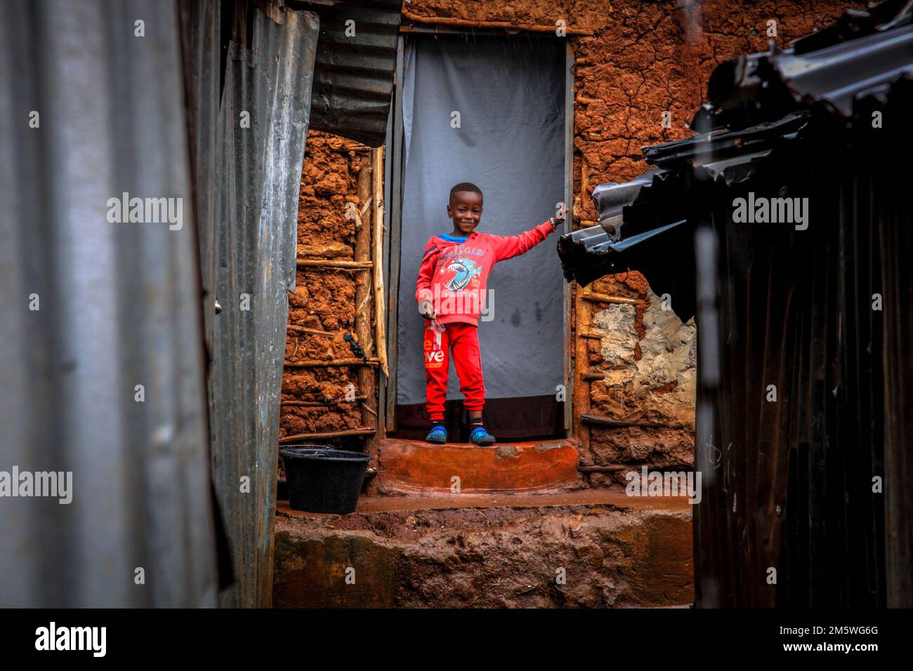 A young boy poses for a photo by the door of his house in Kibera Slum ...