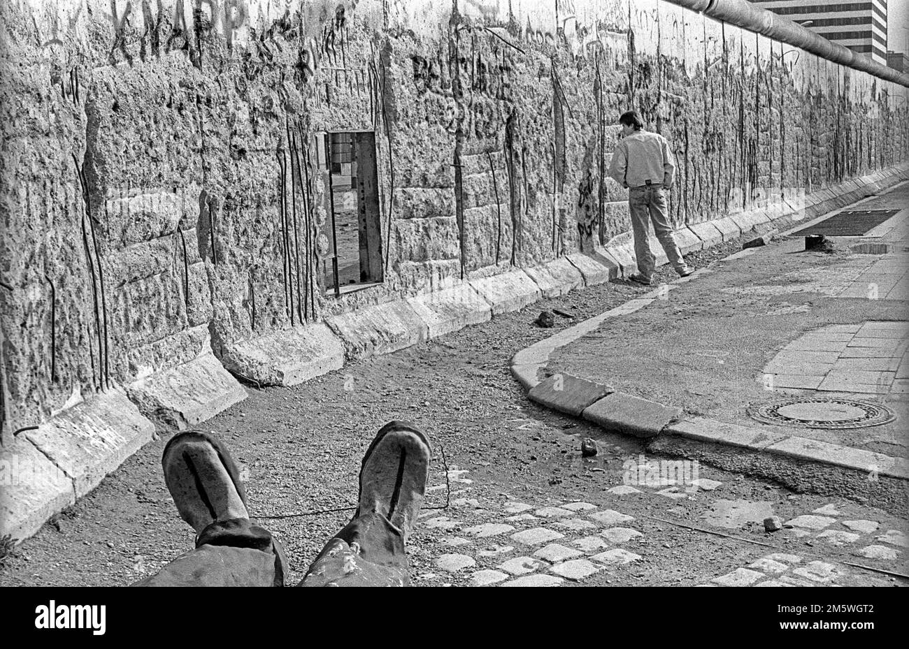 GDR, Berlin, 26. 02. 1990. Wall at Potsdamer Platz, feet, shoes of a ...