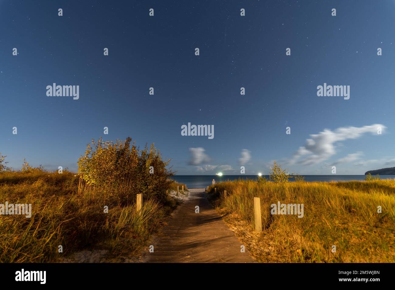 A long exposure shot of a starry night sky over a beach path in the ...