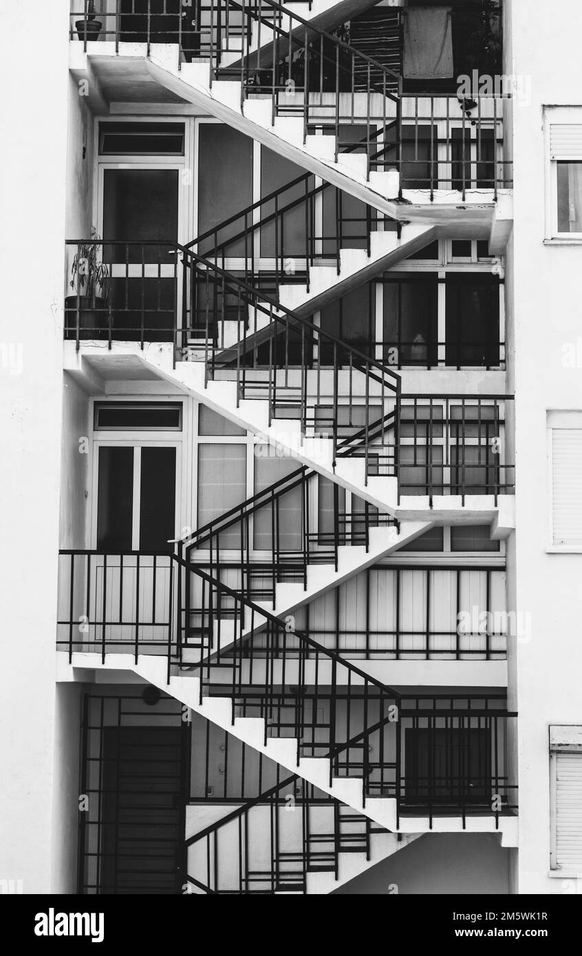 A vertical greyscale shot of a modern building with straight stairs ...