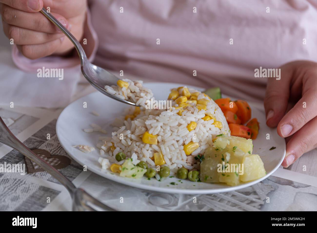 Hand with spoon eating rice and vegetables from a plate. Healthy ...