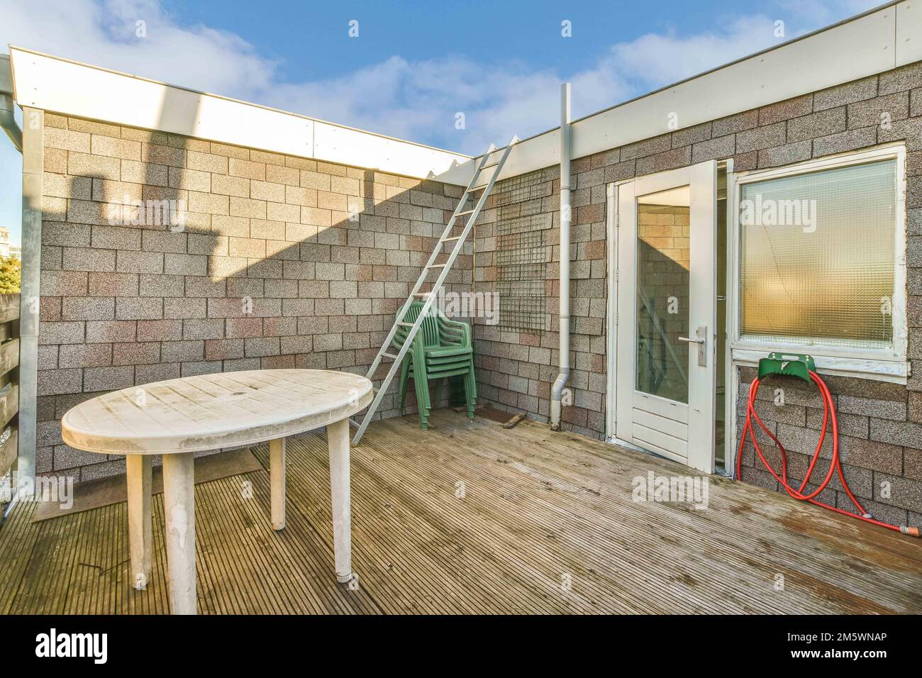 an outside area with a table and ladder on the side of a house that is ...