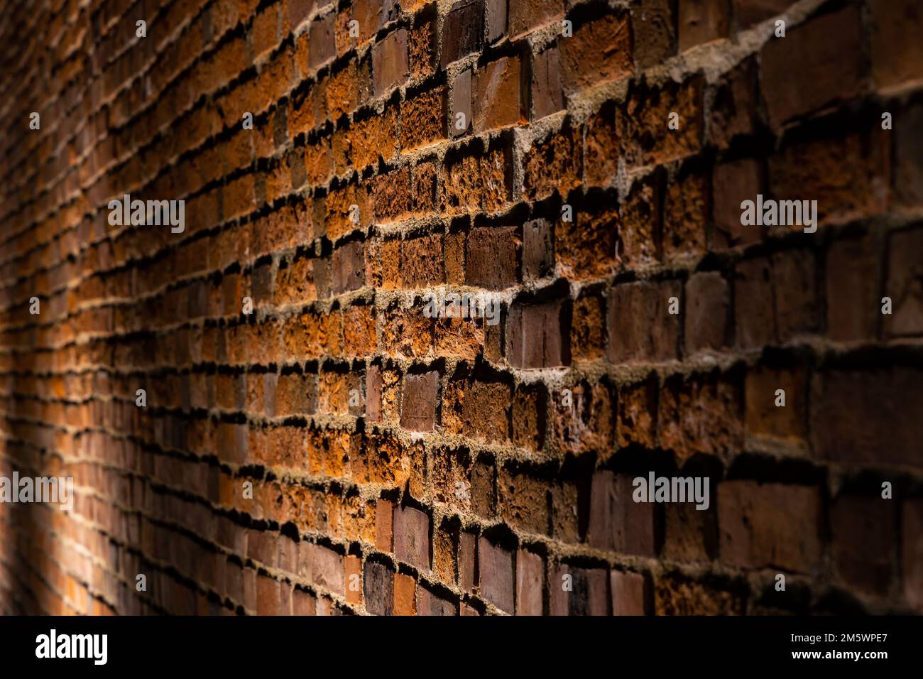 A red brick wall illuminated at night. Surface texture emphasized by ...