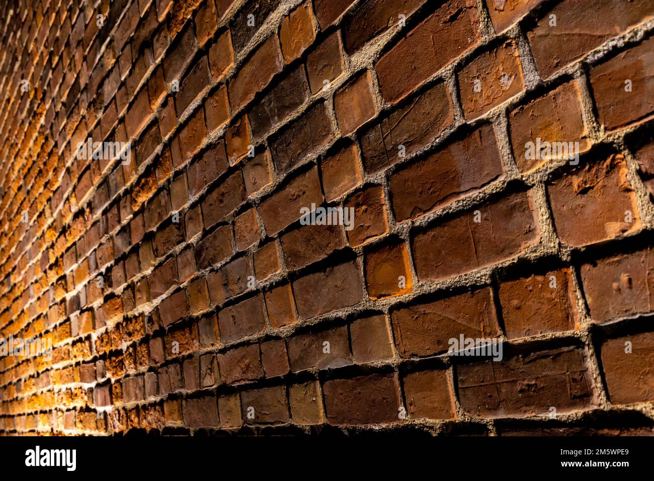 A red brick wall illuminated at night. Surface texture emphasized by ...