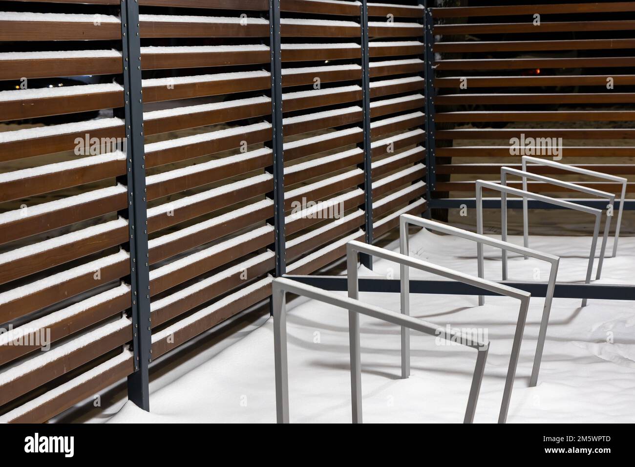 Empty shed with bicycle racks in a city park in winter. Difficulties in ...