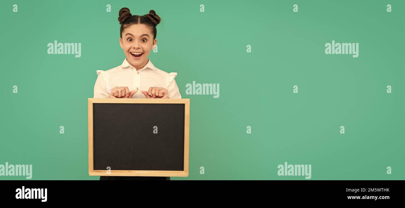 amazed child in school uniform with blackboard on blue background ...