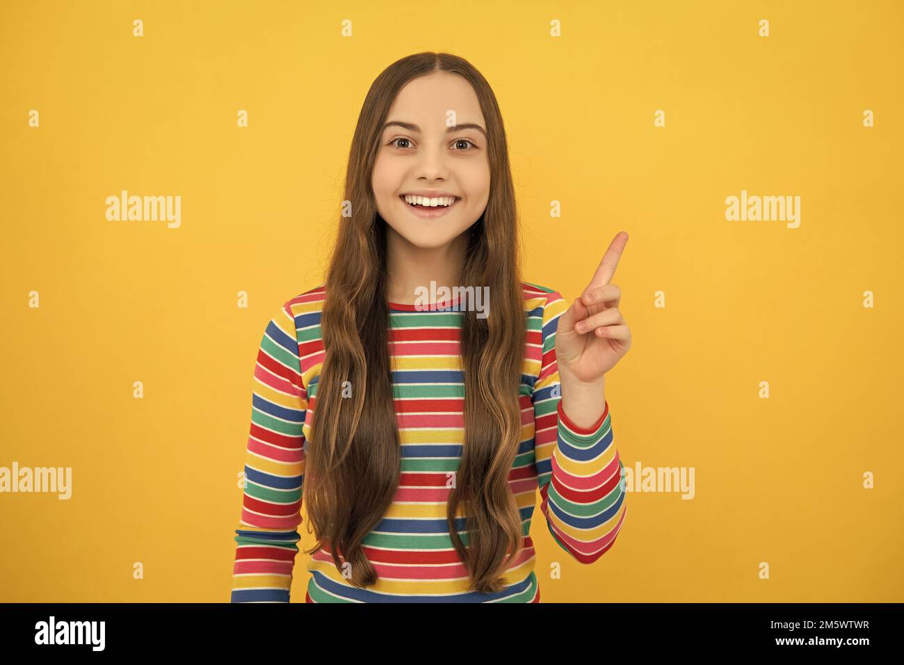 Portrait of cute teenager pointing up with finger. Girl has great new ...