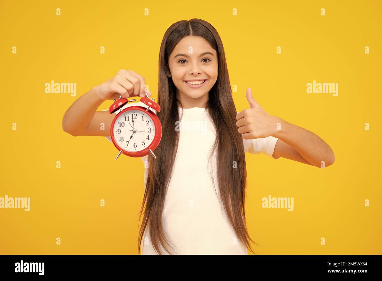 Punctual teen girl checking time. Child with alarm clock showing time ...
