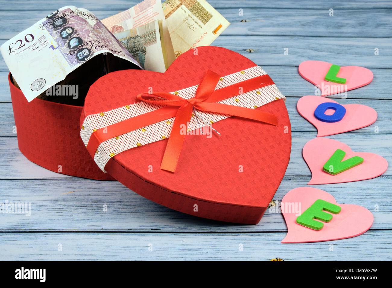 Concept of love of money, in a box that is a heart on top of a blue ...