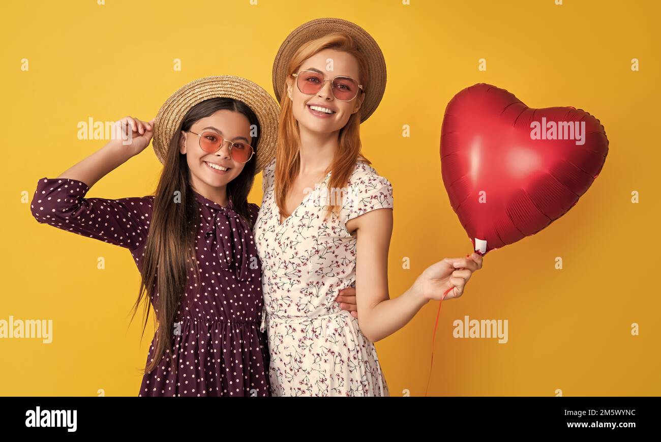 glad mom and daughter hold love heart balloon on yellow background ...