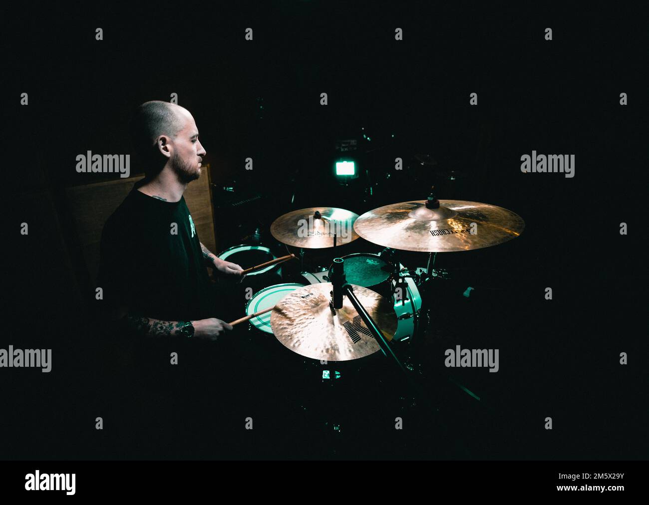 A profile shot of a drummer with tattoos playing in a dark studio Stock ...