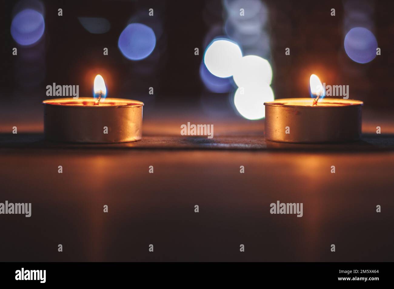 Closeup small candles with bright flame placed on table in dark room ...