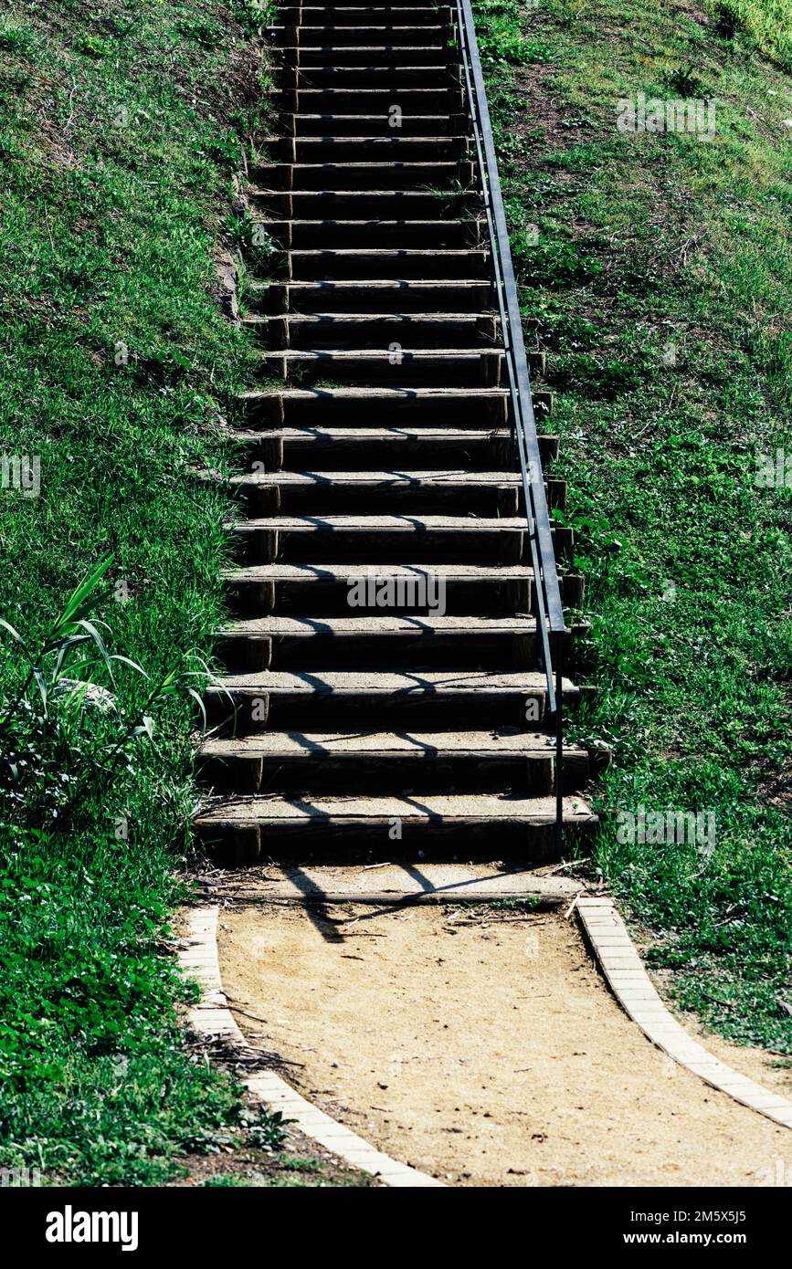 A staircase with a handrail going up the hill covered with meadow Stock ...