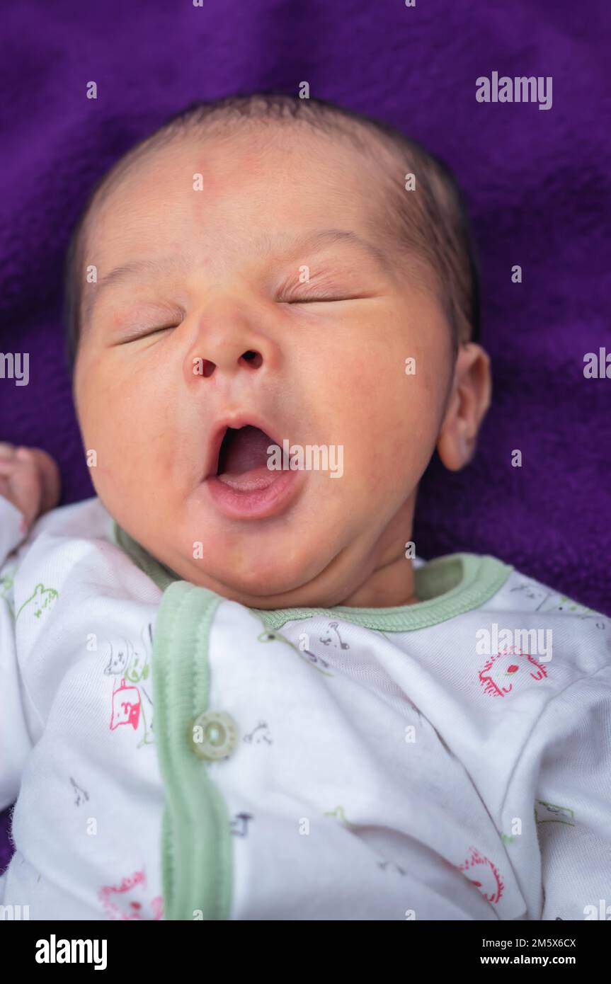 newborn baby isolated yawning in white cloth with purple background ...