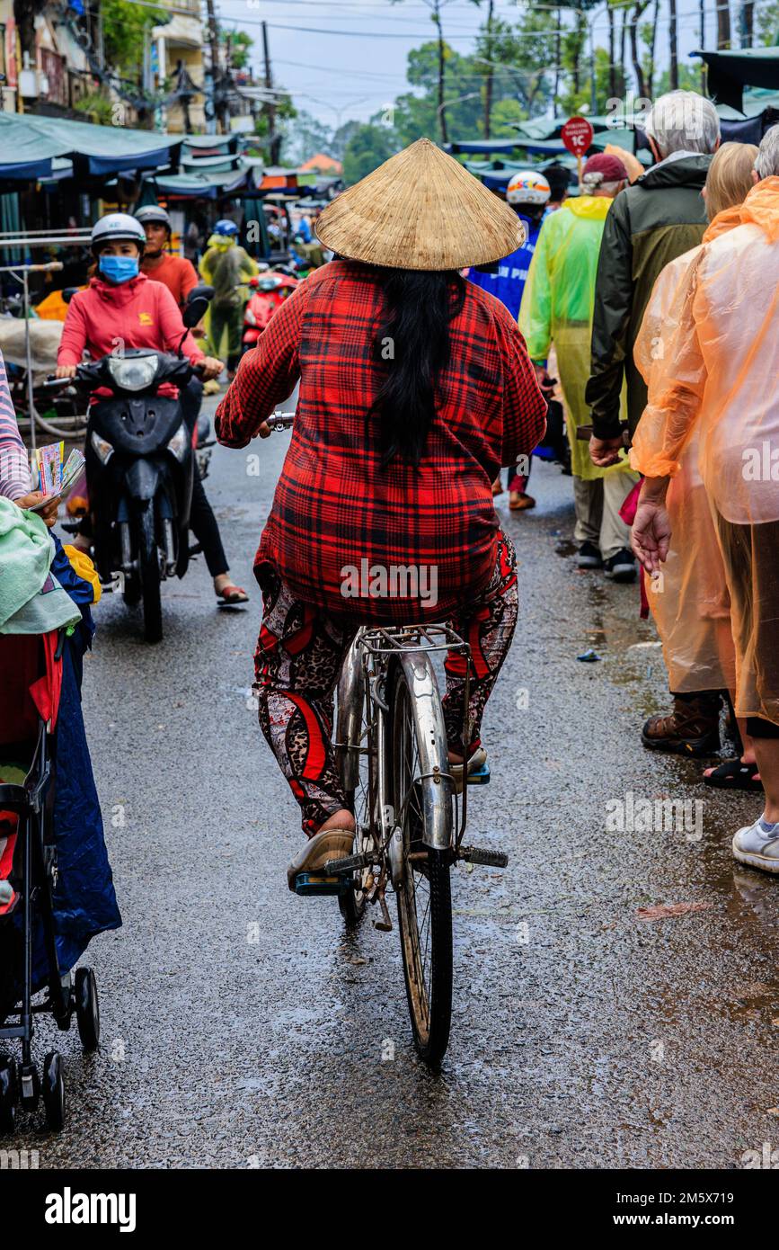 vietnamese lady in traditional red outfit and conical hat cycles her ...