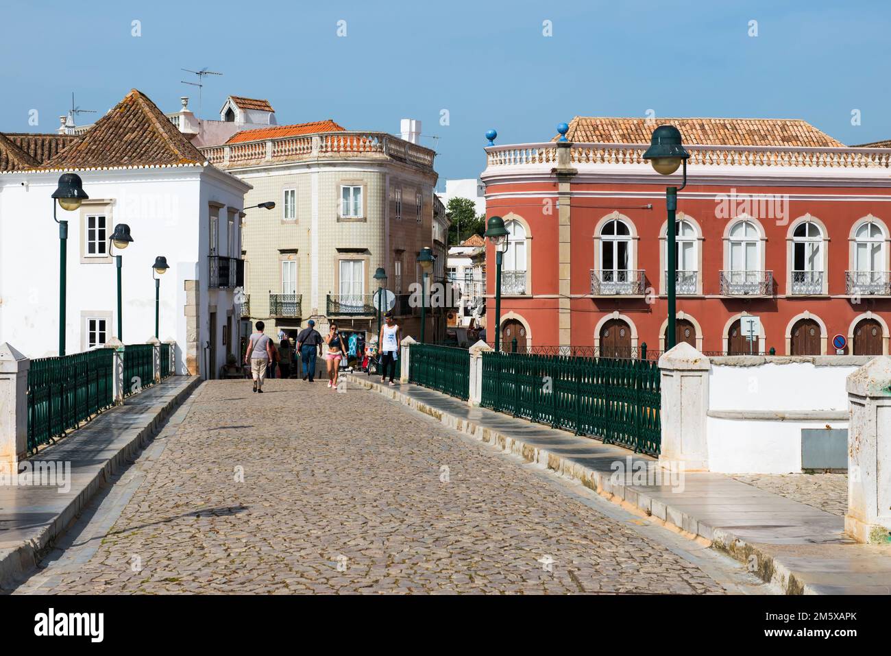 People crossing the Roman Bridge over the Gilao river, Tavira, Algarve ...
