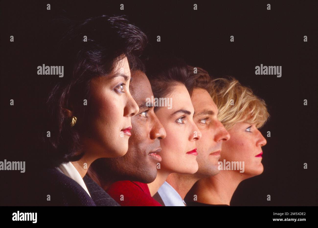 A row of businessmen and women, heads in a line all glancing out at the ...