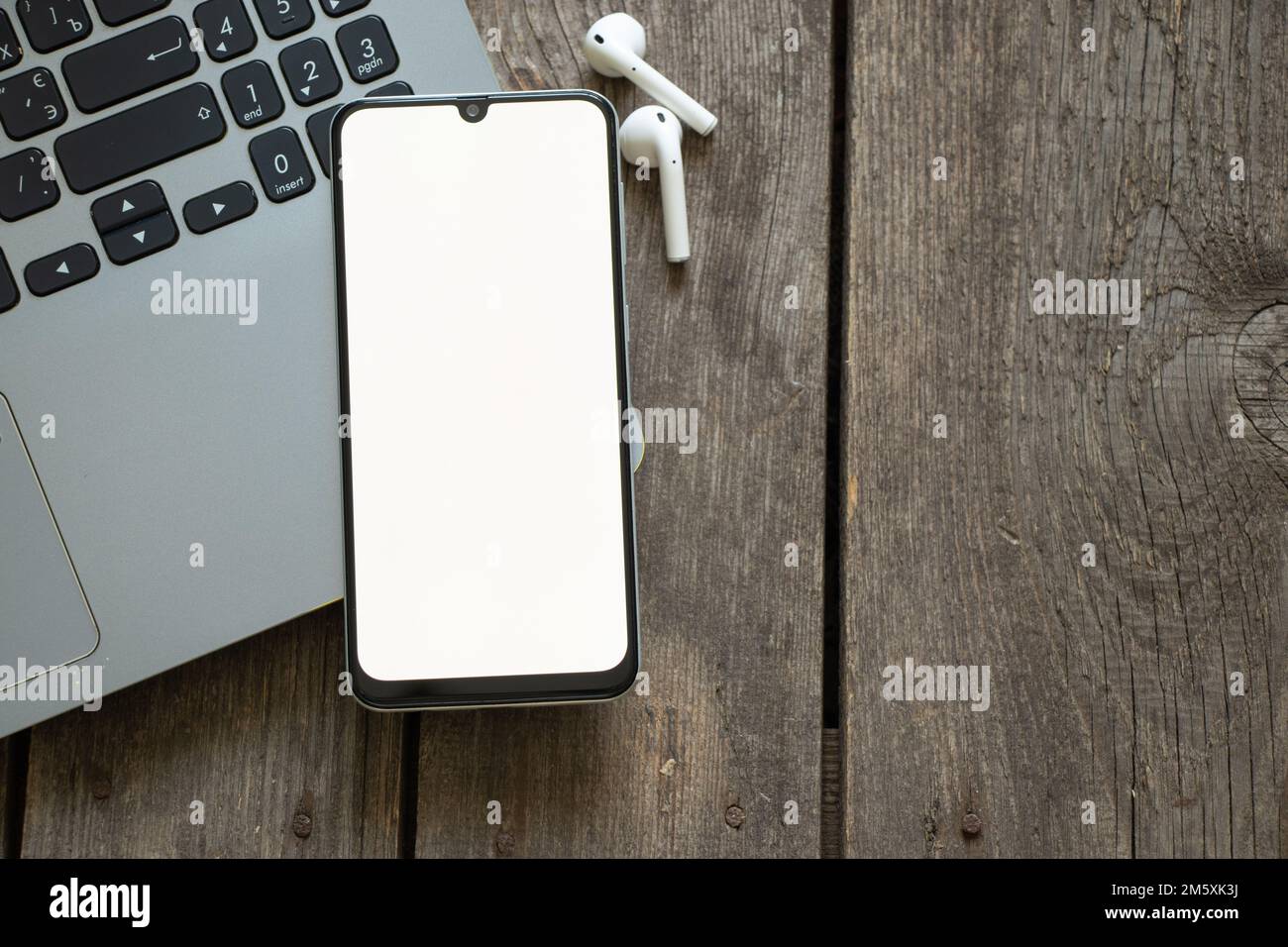 phone with white screen laptop and wireless headphones on wooden table ...