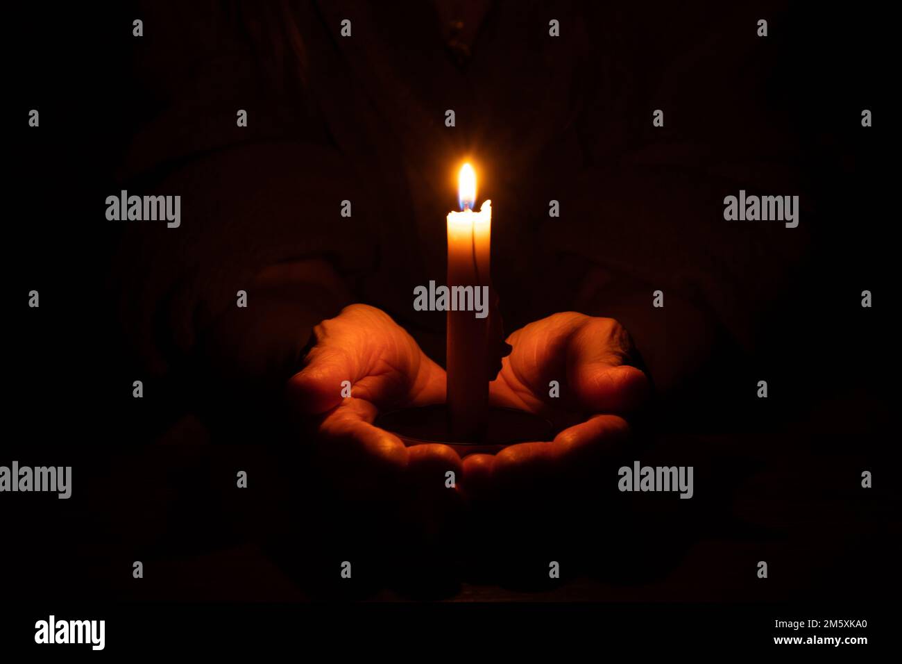 old woman's hands and candle flame in the dark, candle light, mourning ...